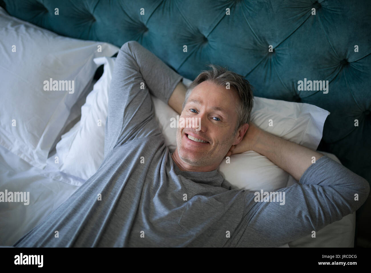 Portrait of smiling man sleeping on bed in bedroom Stock Photo - Alamy