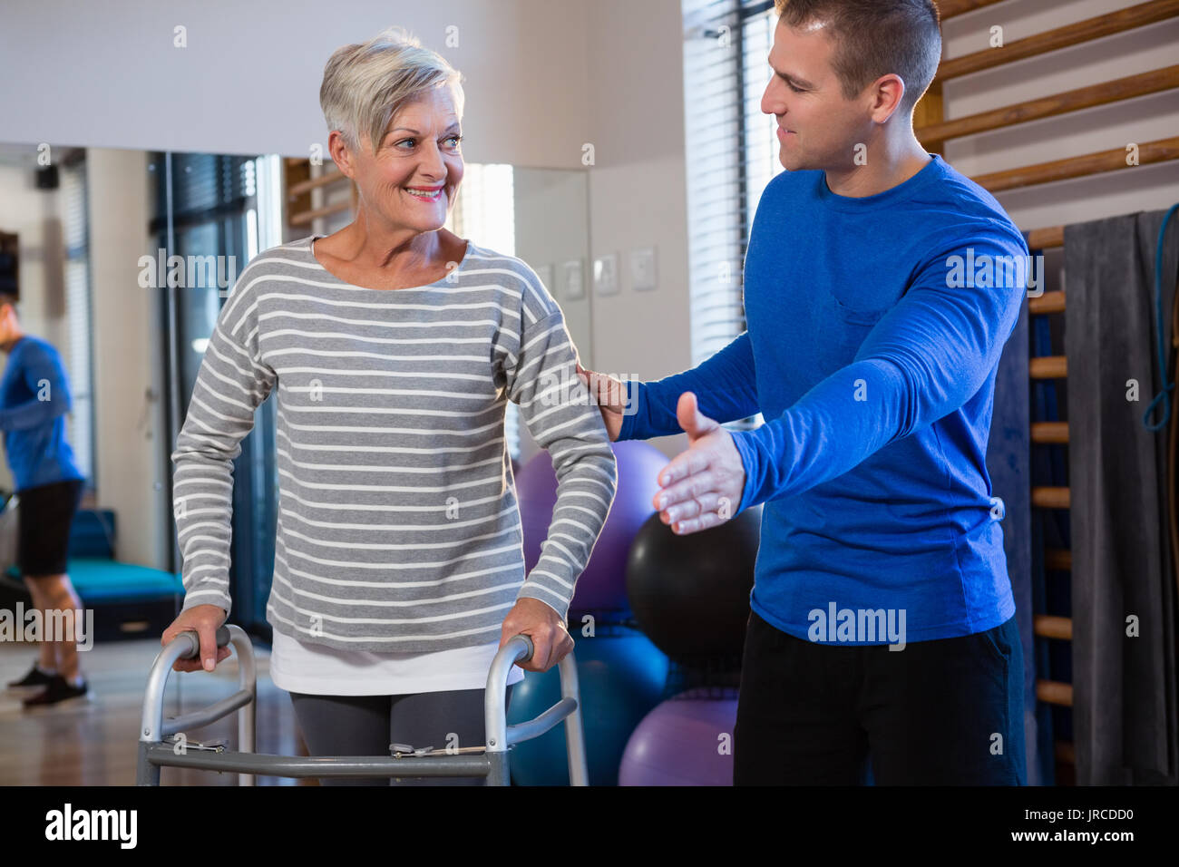 Man helping senior woman to walk with walker in hospital Stock Photo ...
