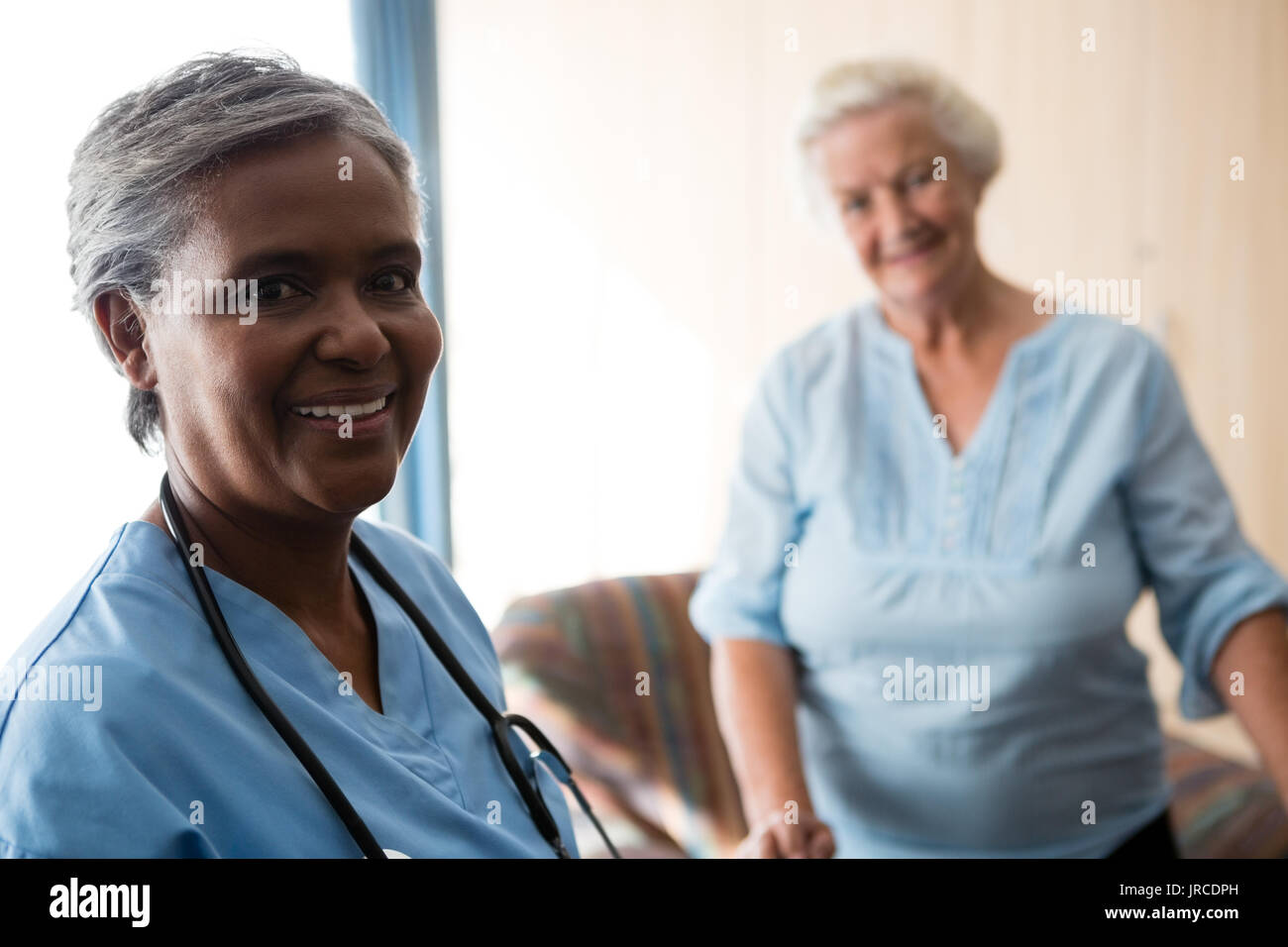 Portrait of nurse and senior patient standing in retirement home Stock ...