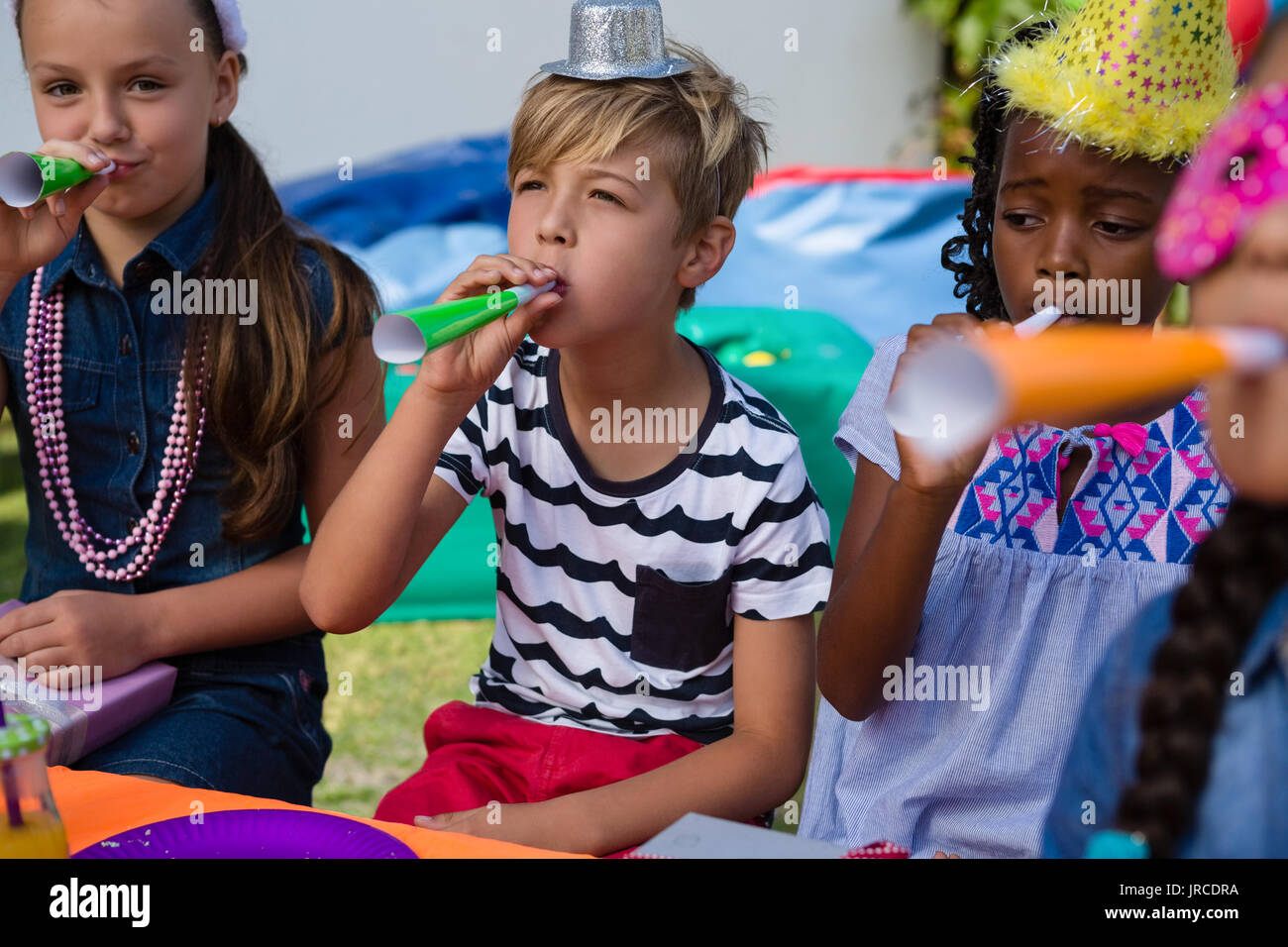 Children blowing part horns during birthday in yard Stock Photo - Alamy