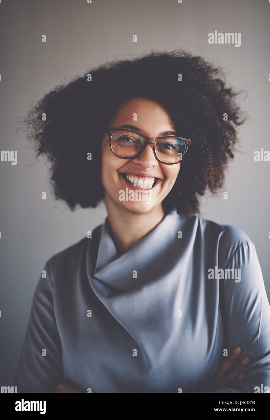 Portrait of a smiling young African businesswoman wearing glasses and ...