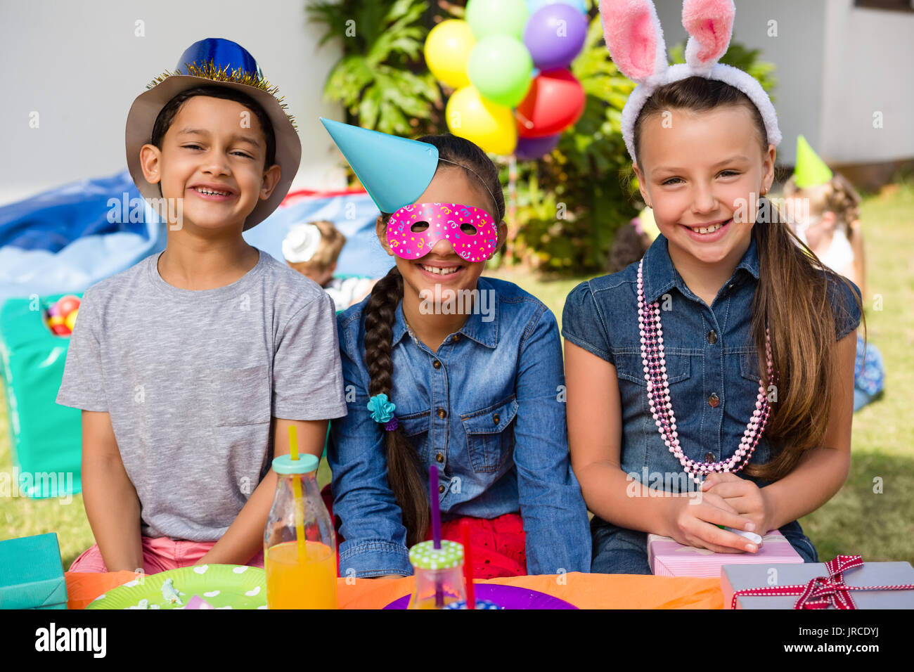 Portrait of happy children sitting at table during birthday party in ...