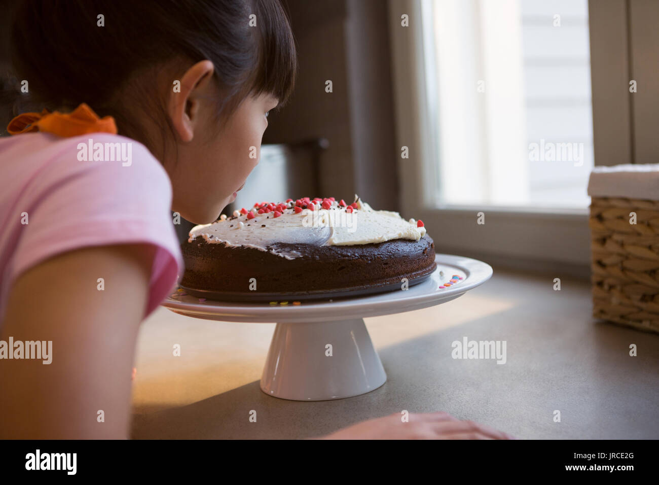 Girl looking at cake in kitchen Stock Photo - Alamy