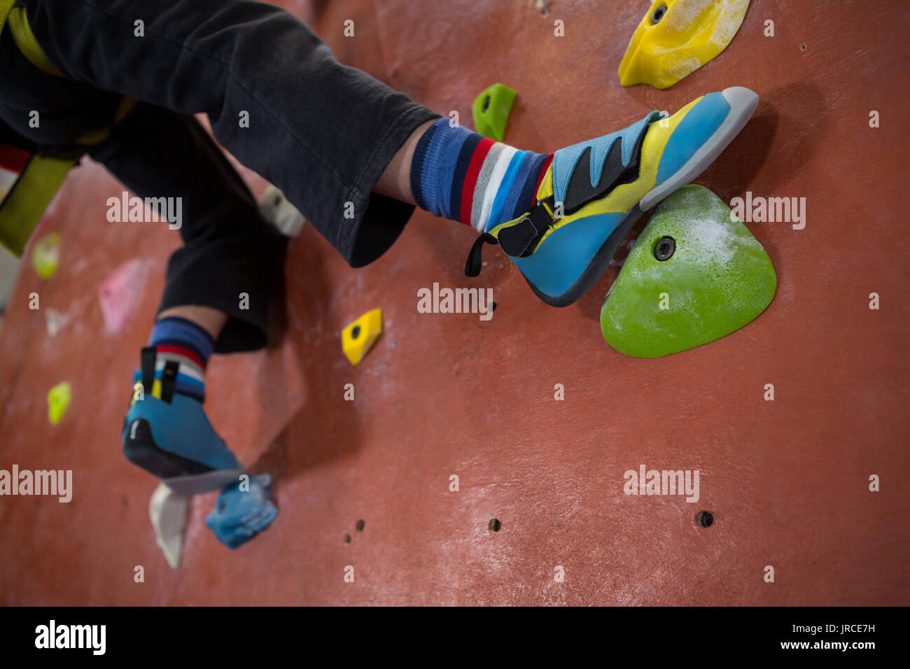 Low-section of boy practicing rock climbing in fitness studio Stock ...