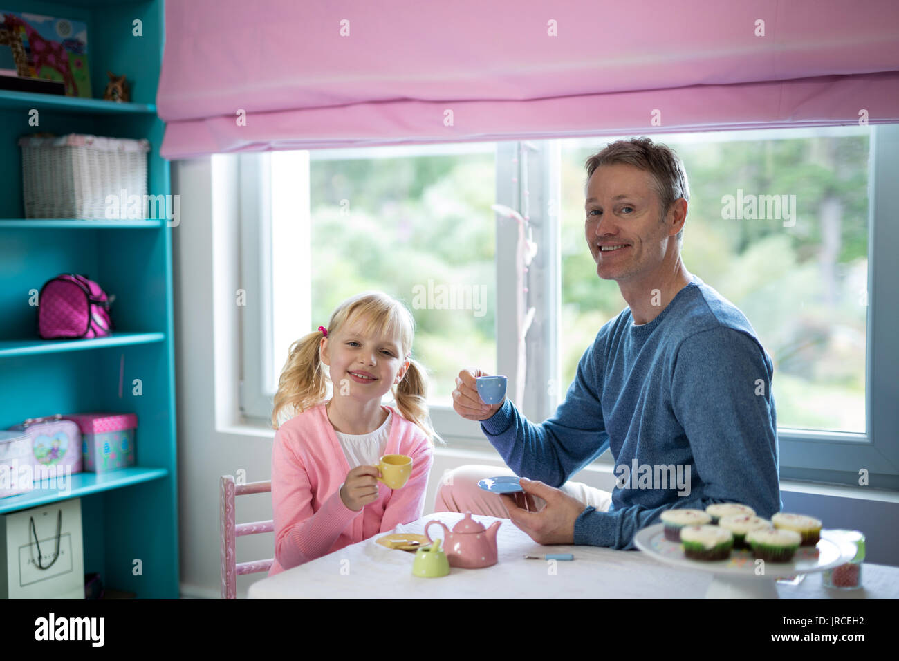 Portrait of father and daughter playing a tea set role play in her room ...