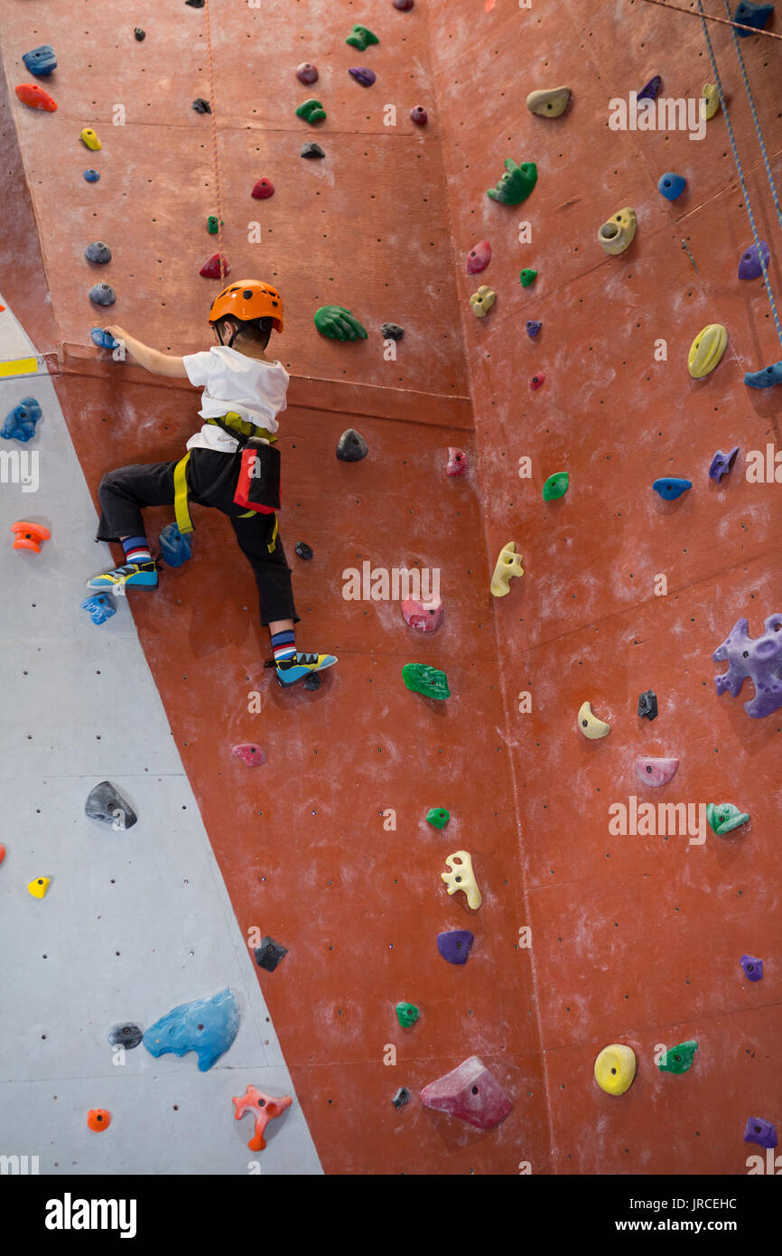 Determined boy practicing rock climbing in fitness studio Stock Photo ...