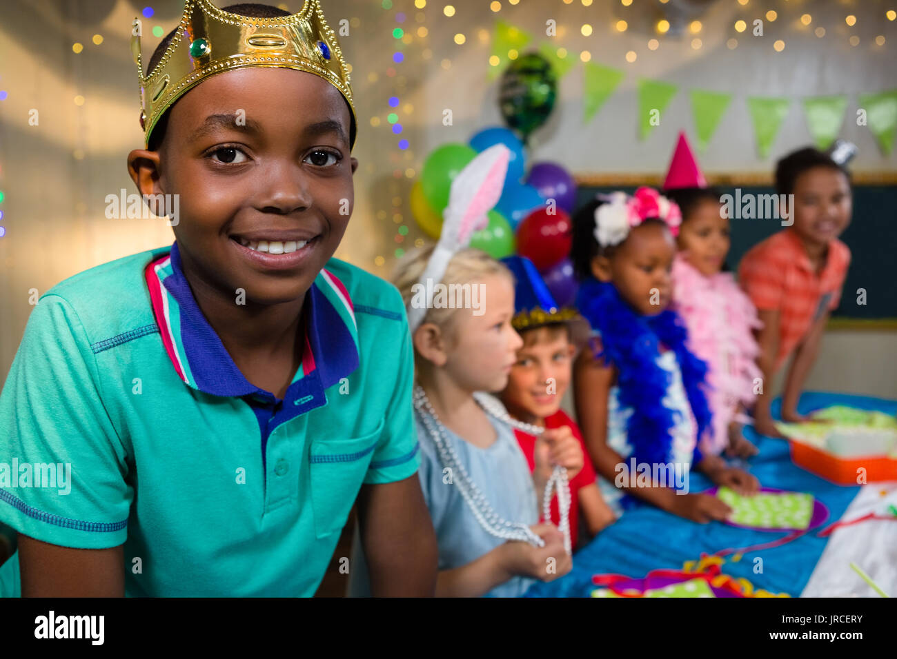 Portrait of boy wearing crown with friends in background during party ...