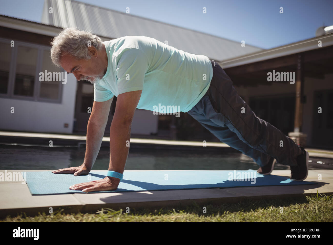 Senior man doing push-up near swimming pool on sunny day Stock Photo ...