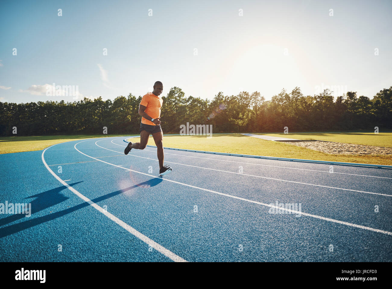 Focused young African male athlete in sportswear racing alone along a ...