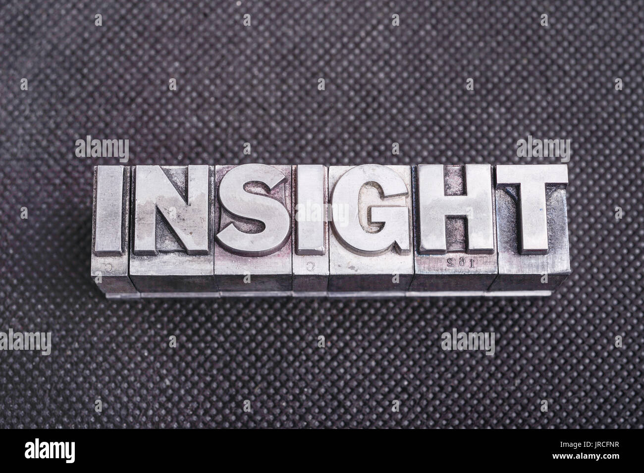 insight word made from metallic letterpress blocks on black perforated ...