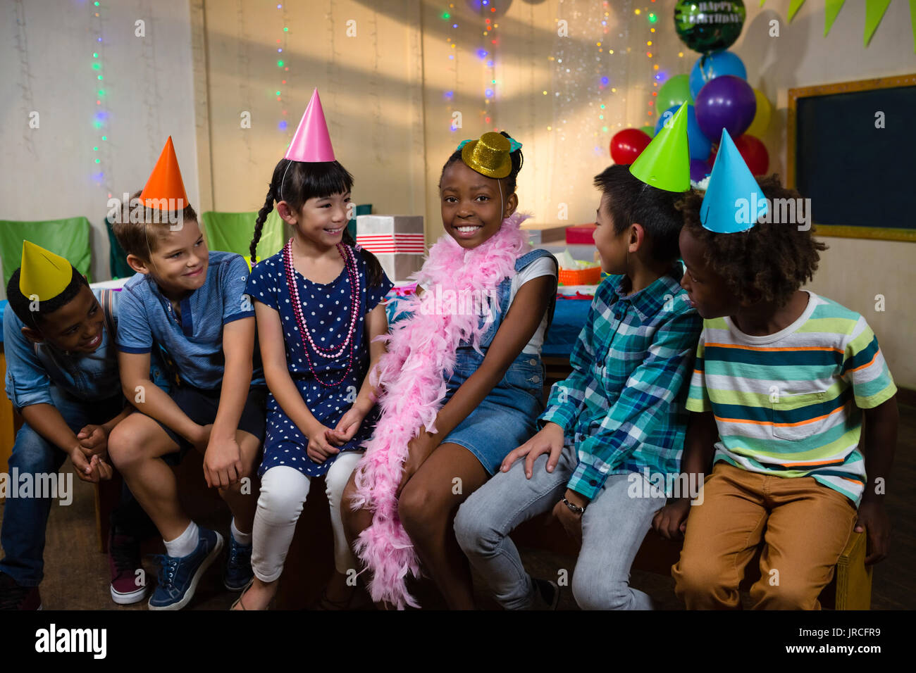 Happy children sitting against wall during birthday party Stock Photo ...