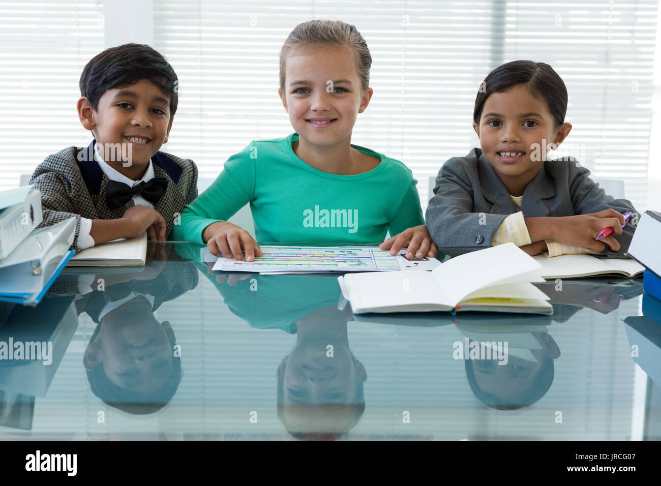 Portrait of smiling kids discussing while sitting in boardroom Stock ...