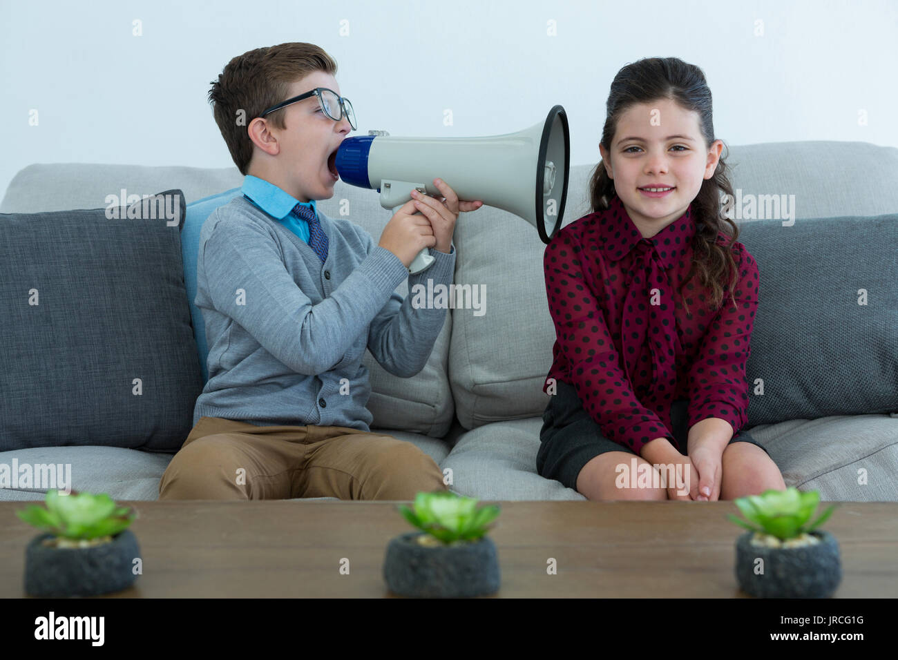 Businessman shouting through megaphone into female colleagues ear at ...