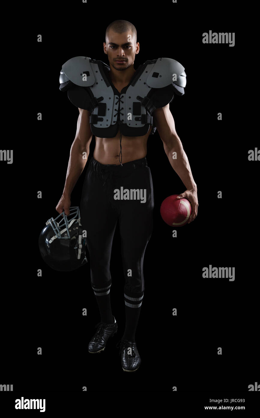 Portrait of muscular American football player holding football and head ...