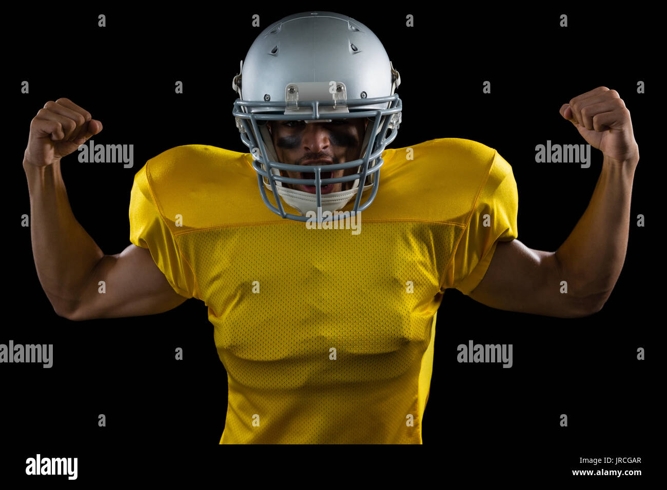 Portrait of American football player flexing his muscles against a ...