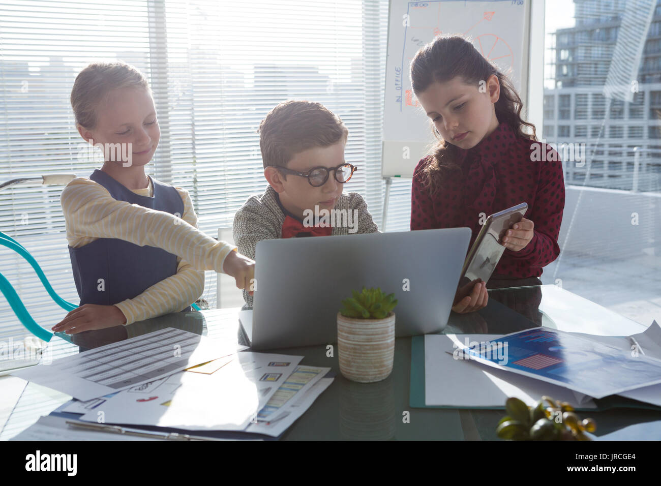 Kids working at table in office Stock Photo - Alamy