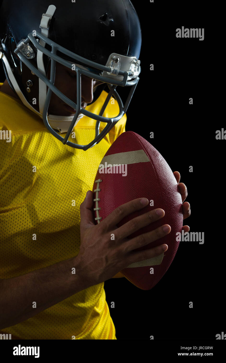 American football player holding a football with both his hands against ...