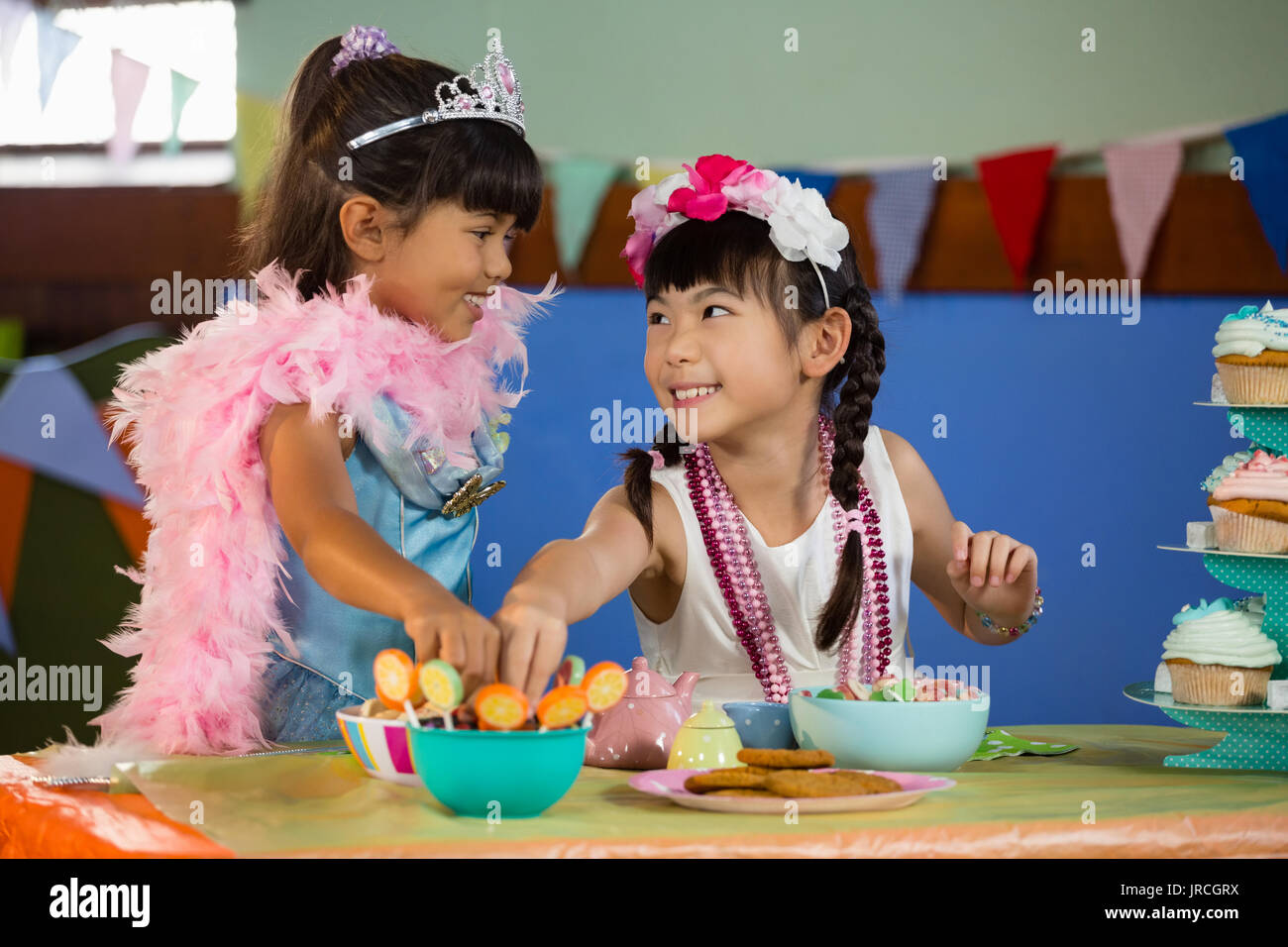 Cute girl having confectionery during birthday party at home Stock ...