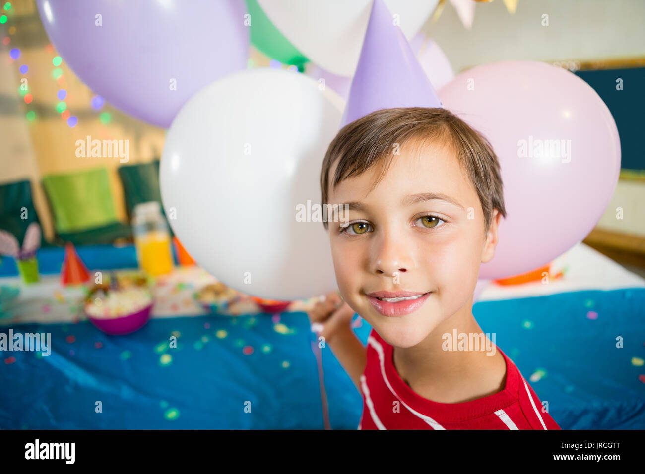 Portrait of cute boy holding colorful balloons during birthday party ...