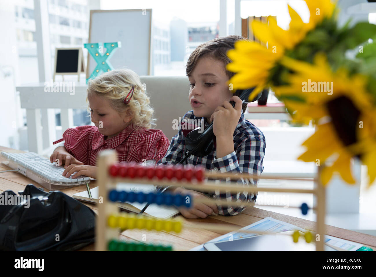 Businesswoman using computer while male coworker talking on phone in ...