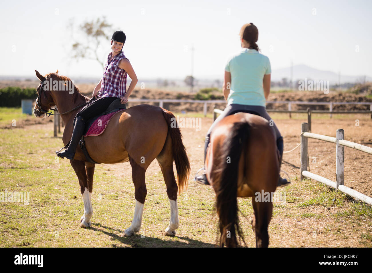 Female friends horseback riding on field during sunny day Stock Photo ...