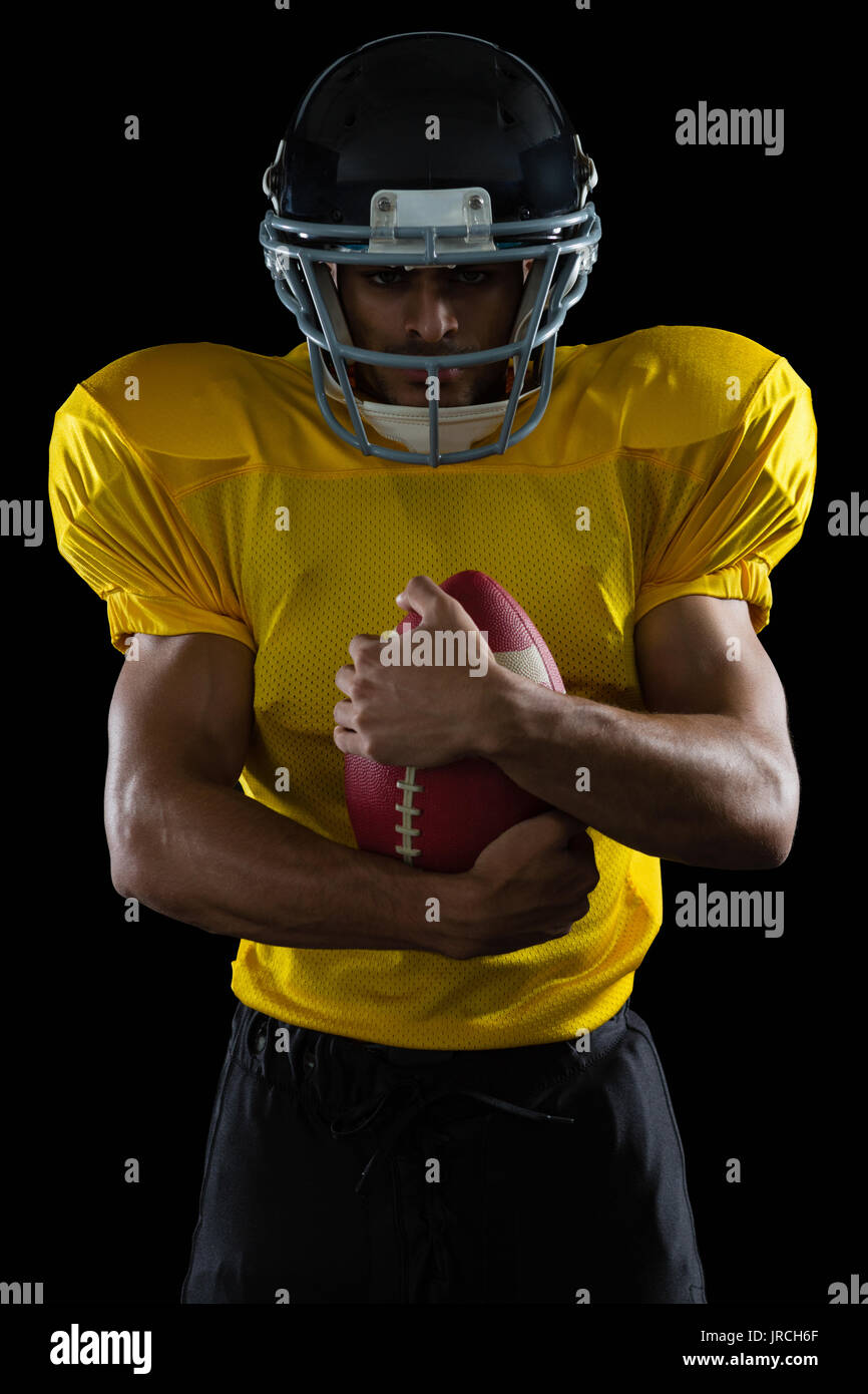 Portrait of American football player holding a ball in both his arms ...