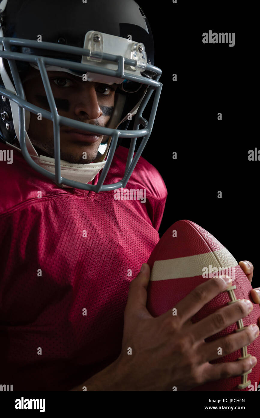 Portrait of American football player holding a football with both his ...