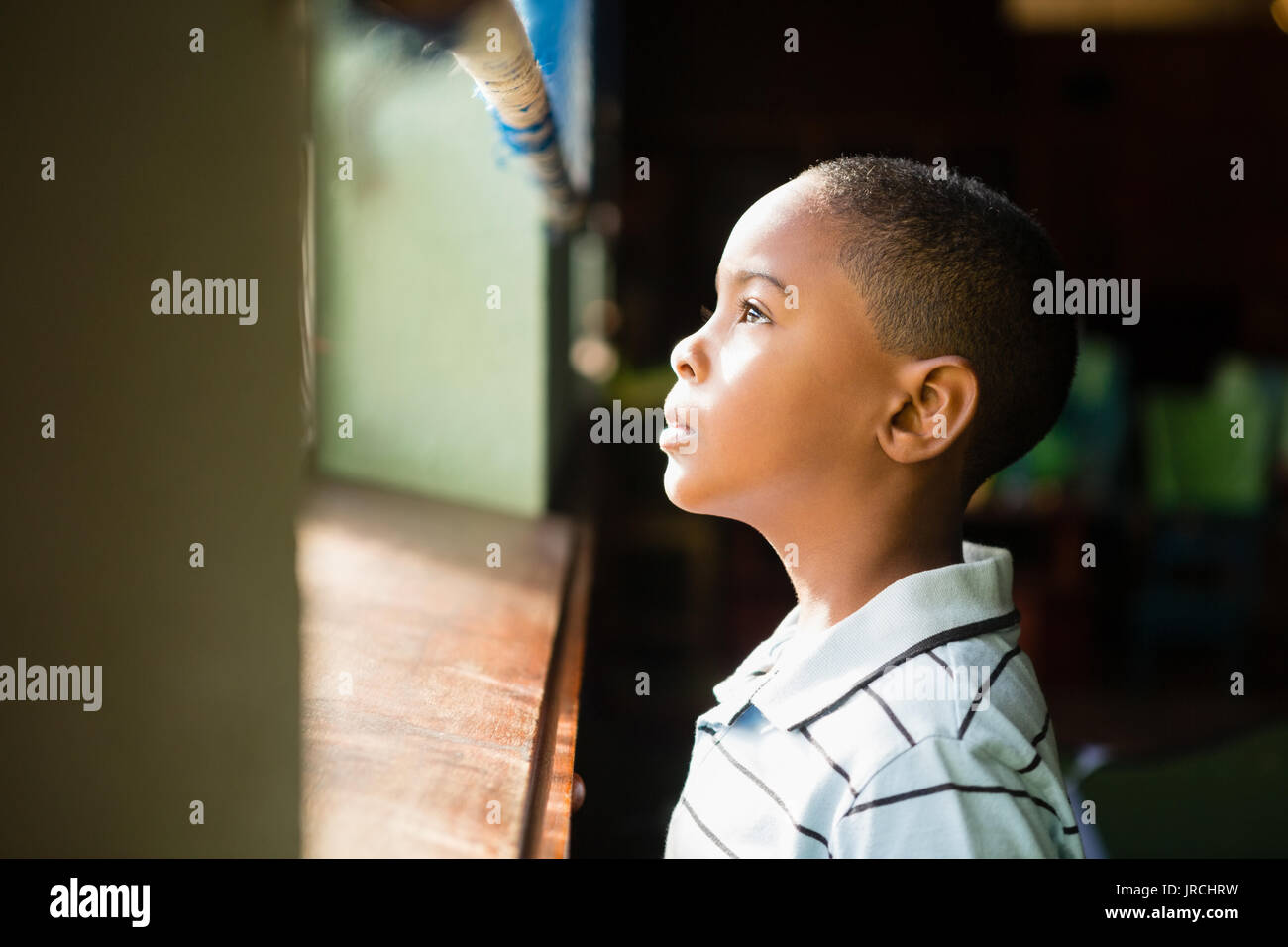 Thoughtful boy looking through window at home Stock Photo - Alamy