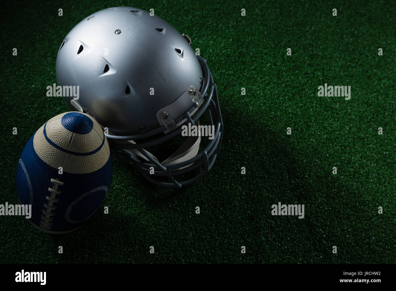 American football leaning on headgear against black background Stock ...
