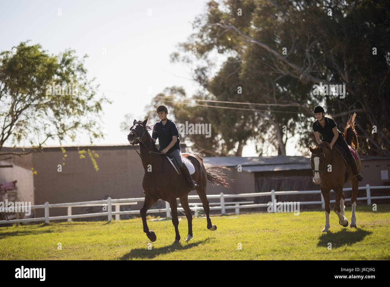 Female friends riding horse at equestrian center Stock Photo - Alamy