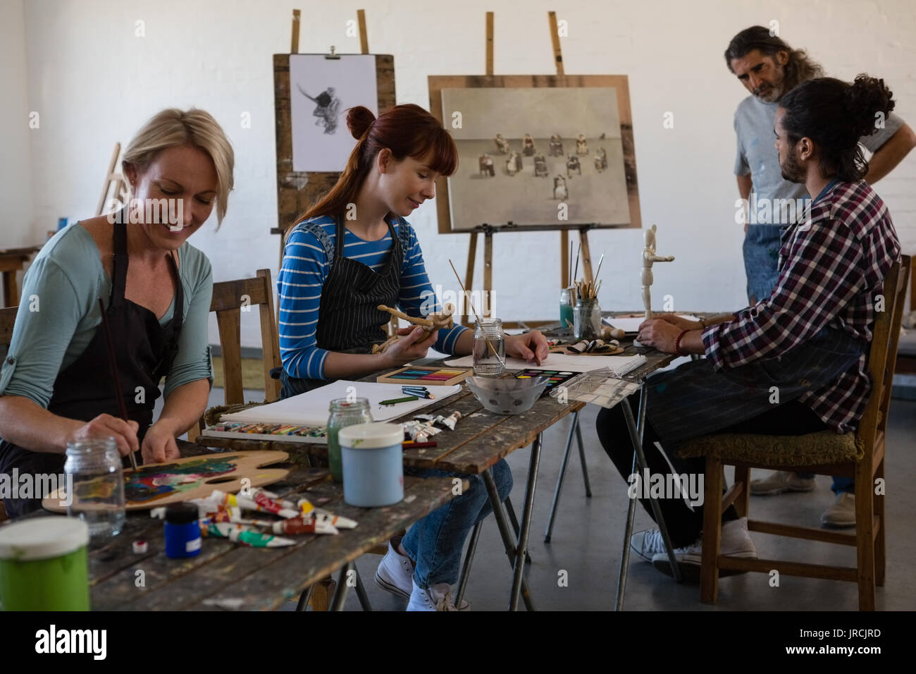 Teacher looking students practicing painting in art class Stock Photo ...