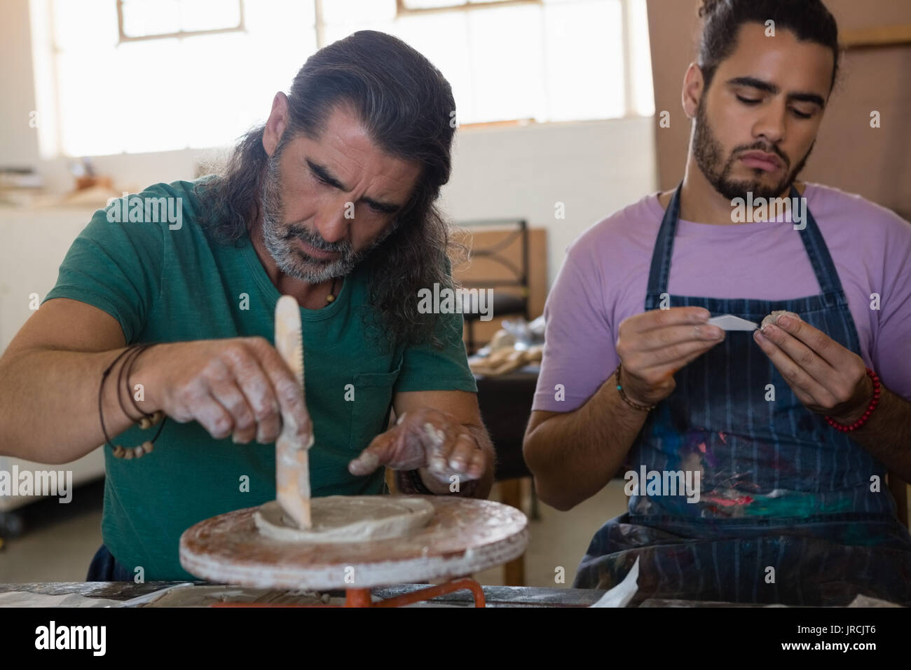 Male adult students making clay product at table in art class Stock ...
