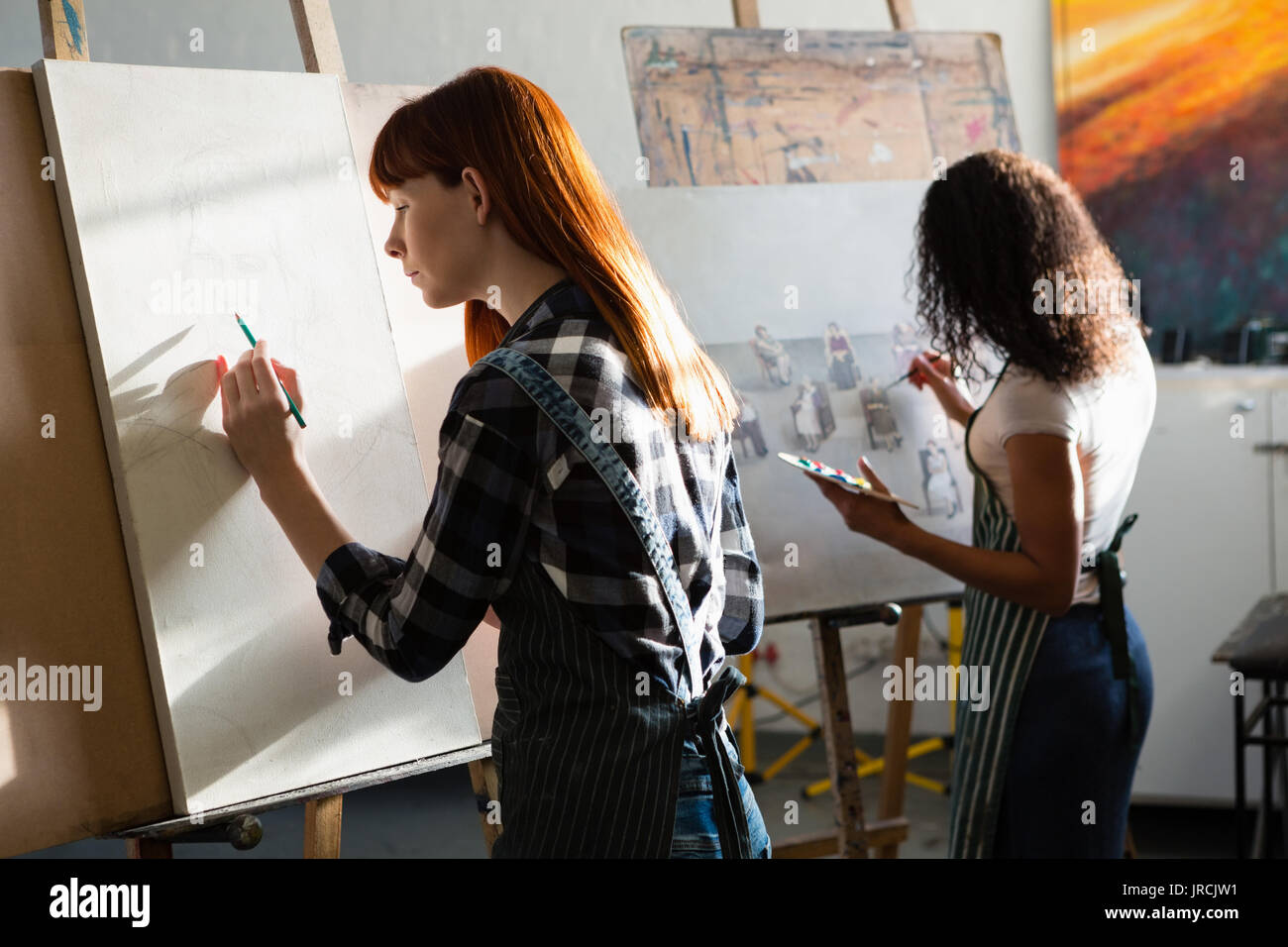 Side view of female artists painting on canvas in art class Stock Photo ...