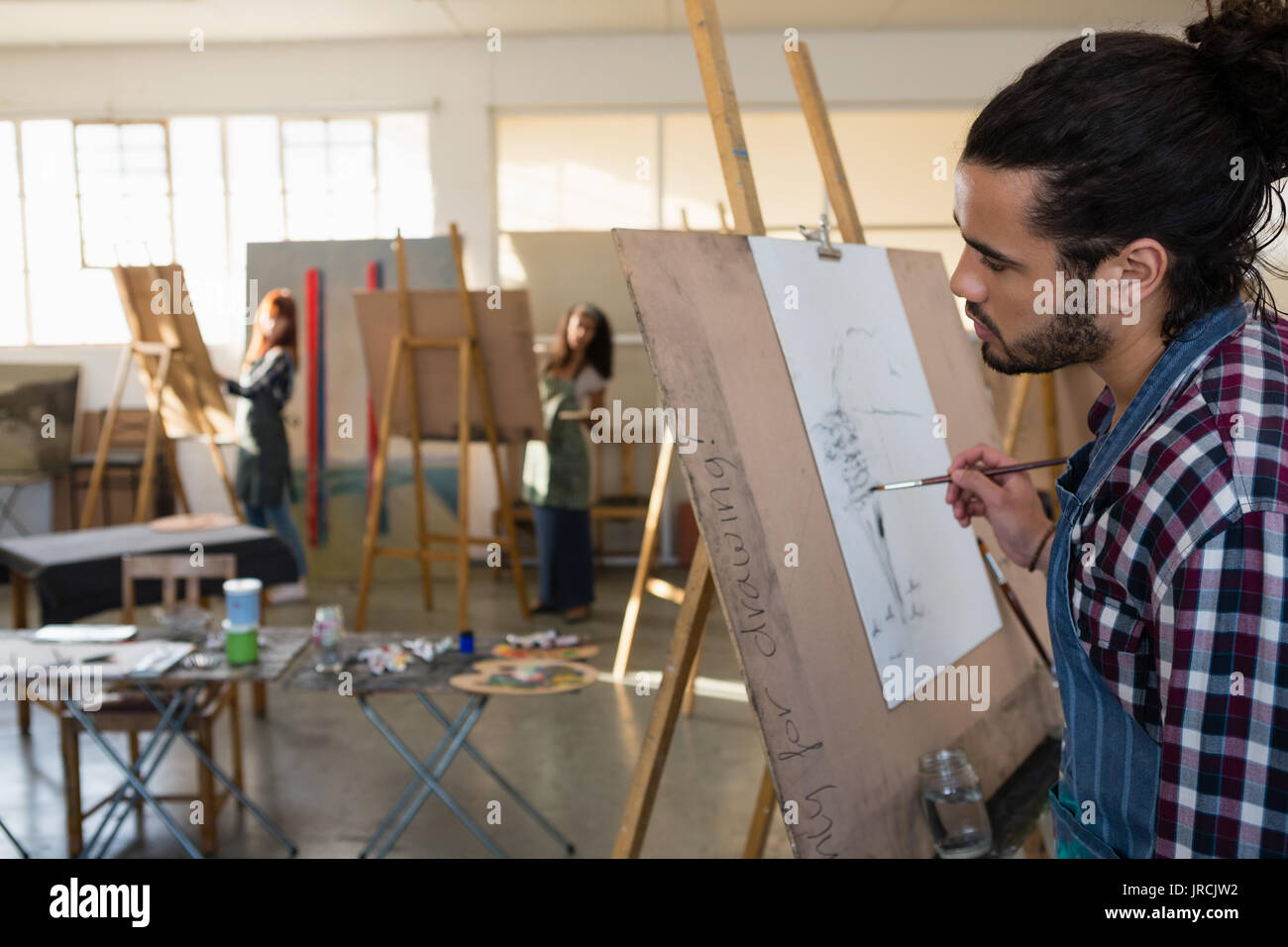 Man painting on paper in art class Stock Photo - Alamy