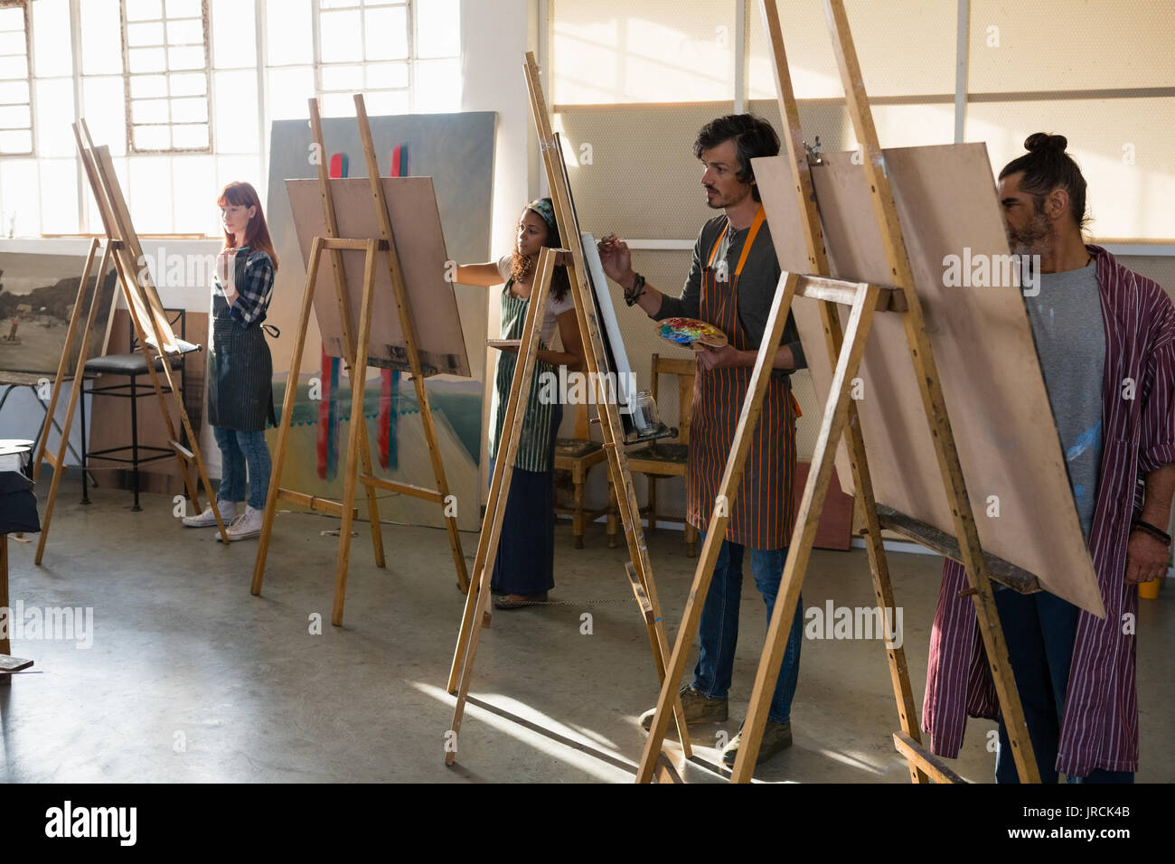 Painters painting on canvas in art class Stock Photo - Alamy