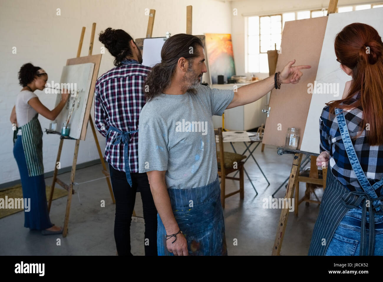 Man assisting artist painting on canvas in art class Stock Photo - Alamy