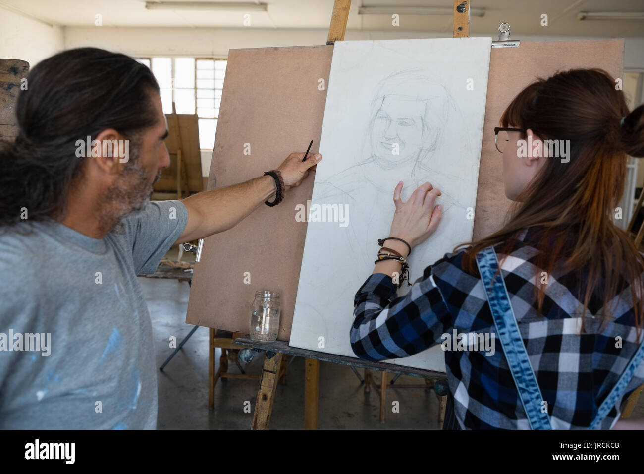 Man assisting woman sketching in canvas in art class Stock Photo - Alamy