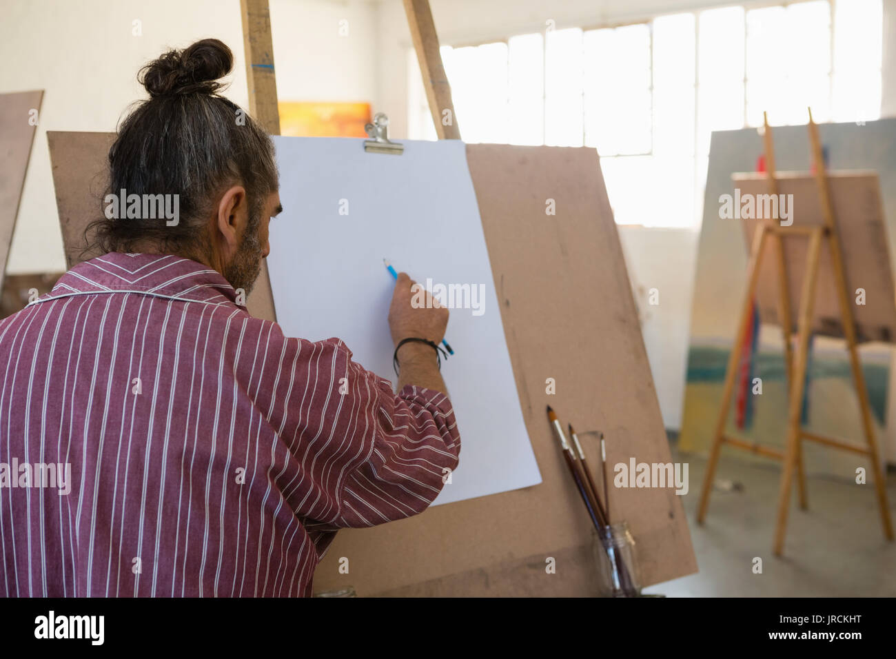 Rear view of man painting on paper in art class Stock Photo - Alamy