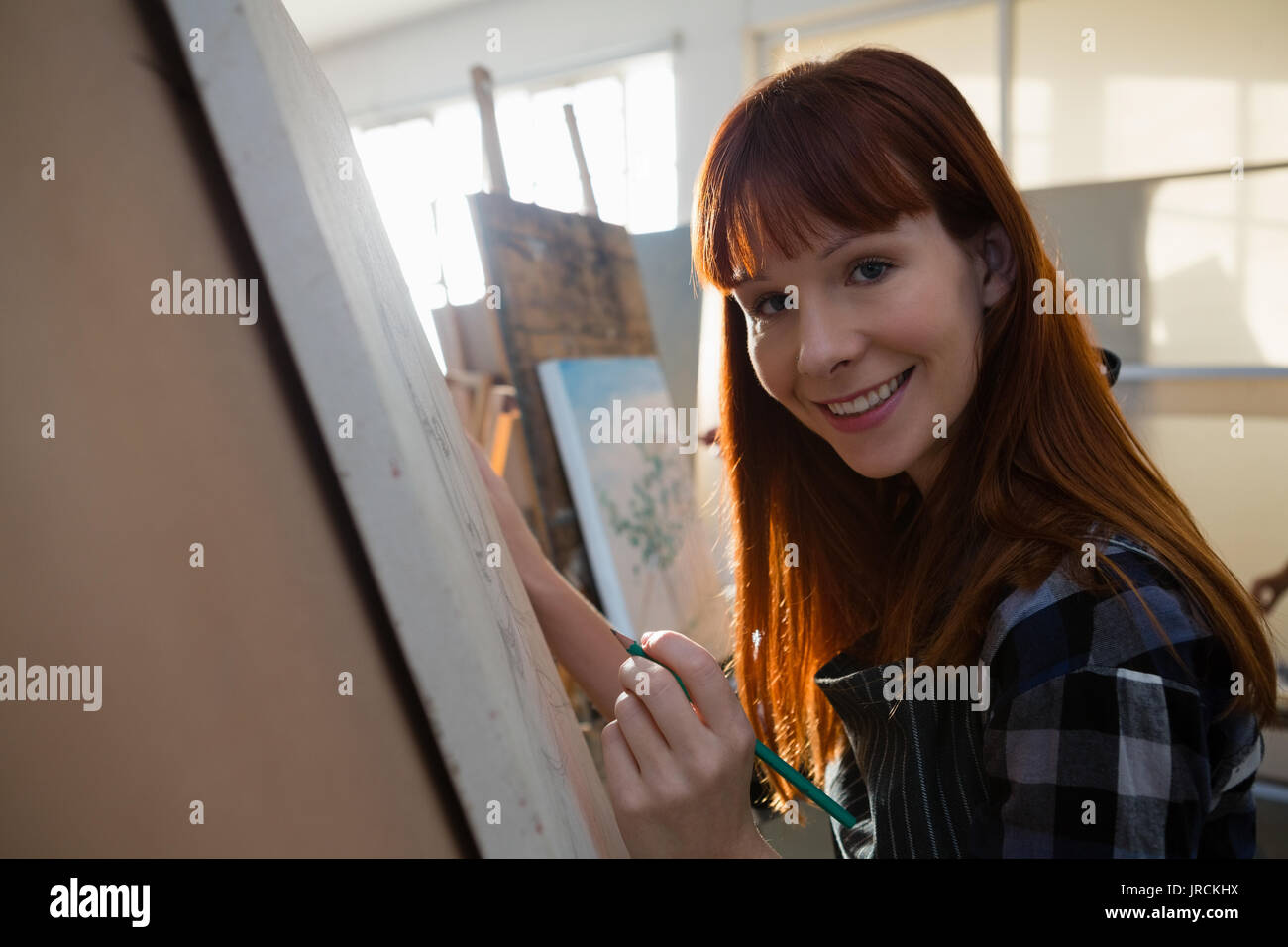 Portrait of smiling woman drawing on canvas in art class Stock Photo ...