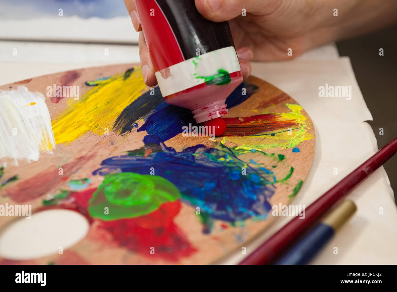 Hand of woman putting red color in palette at drawing class Stock Photo ...