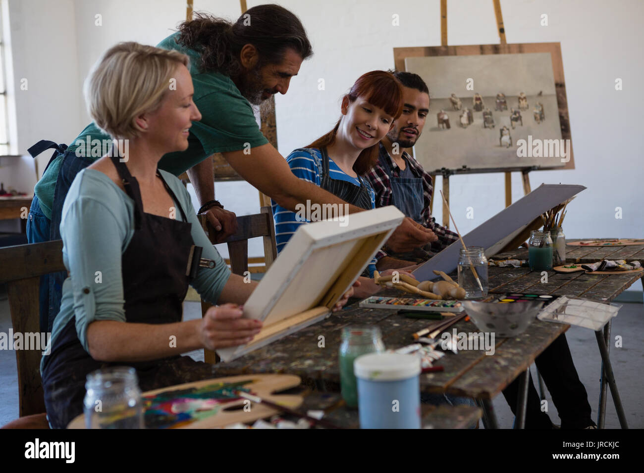 Teacher assisting student for painting in art class Stock Photo - Alamy
