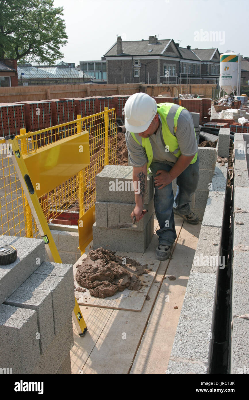 A bricklayer builds a wall using thermal concrete blocks on a ...