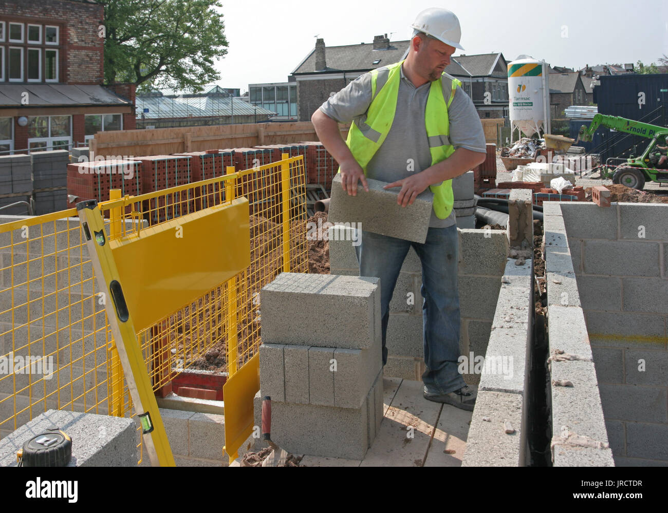 A bricklayer builds a wall using thermal concrete blocks on a ...