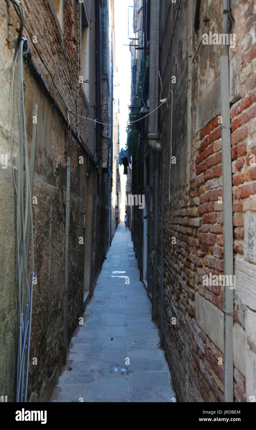 Narrow street with the walls of homes almost touching and the sky just ...