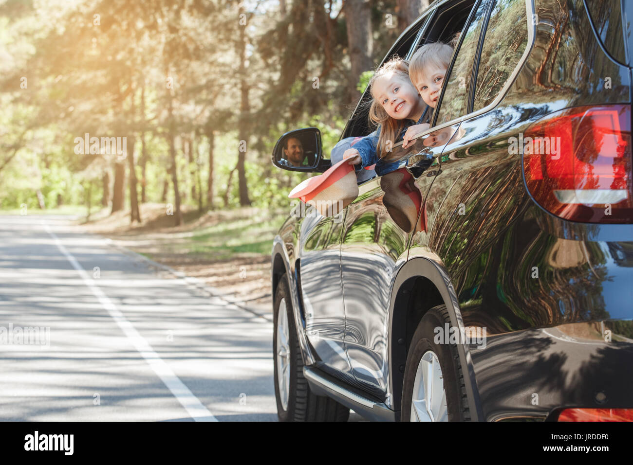 Travel by car family ride together brother and sister lean out of the ...