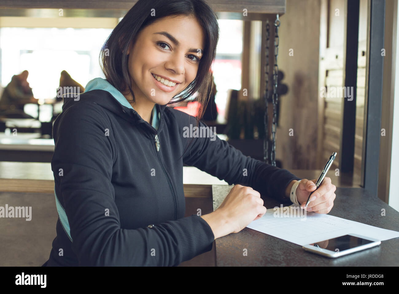Young female sitting indoor sportswear healthy lifestyle taking notes ...