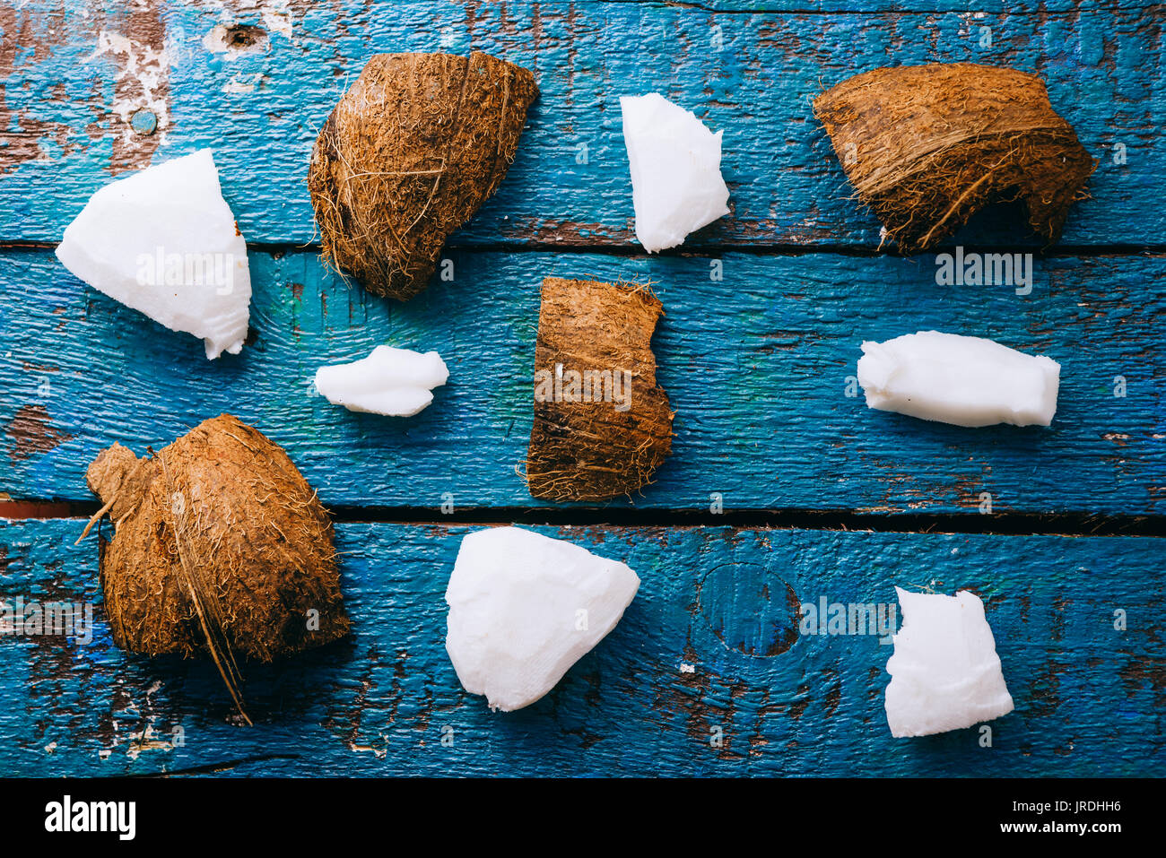 Top view of coconut flesh and hard coconut over a rusty blue background ...