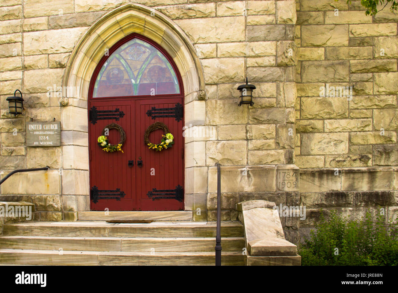 Stone steps lead to the entry red doors of the United Church of Christ ...