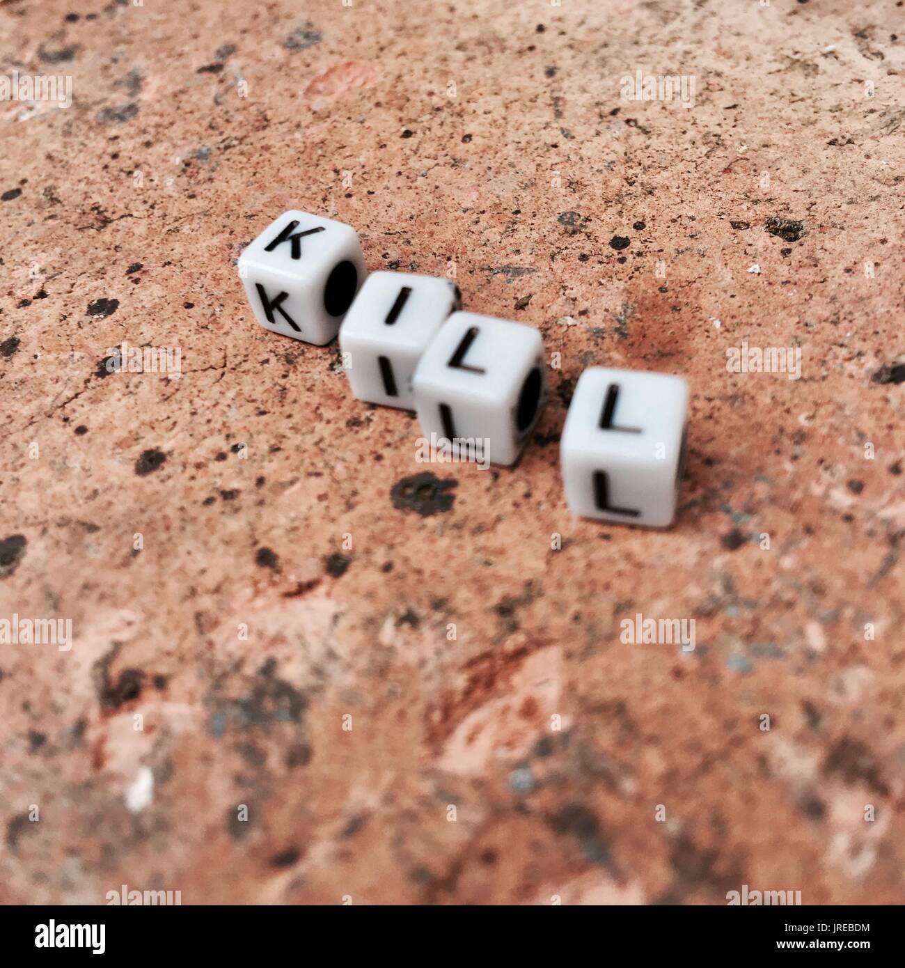 White inscription. Small white square letters. Kill on the brown brick ...