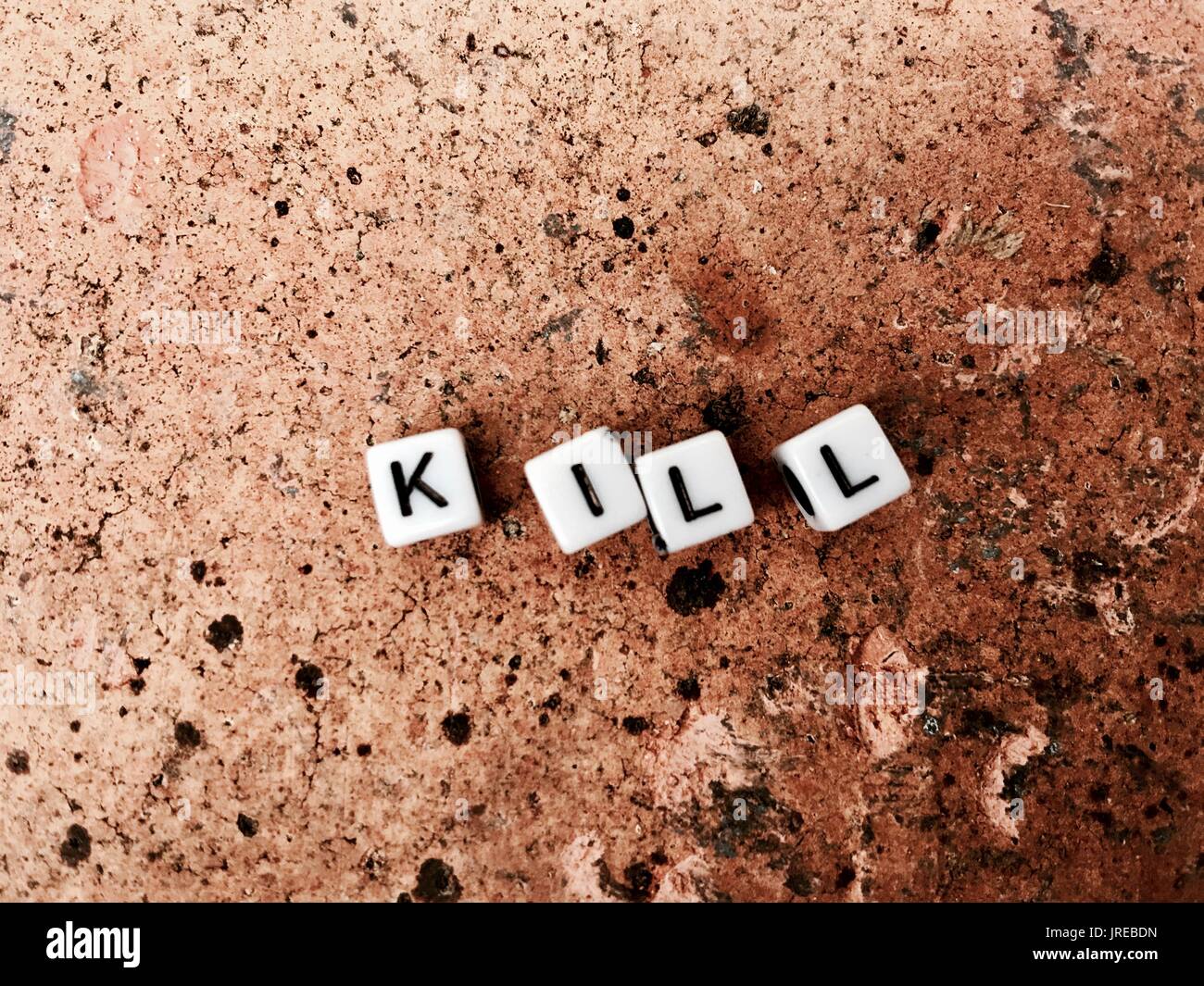 White inscription. Small white square letters. Kill on the brown brick ...